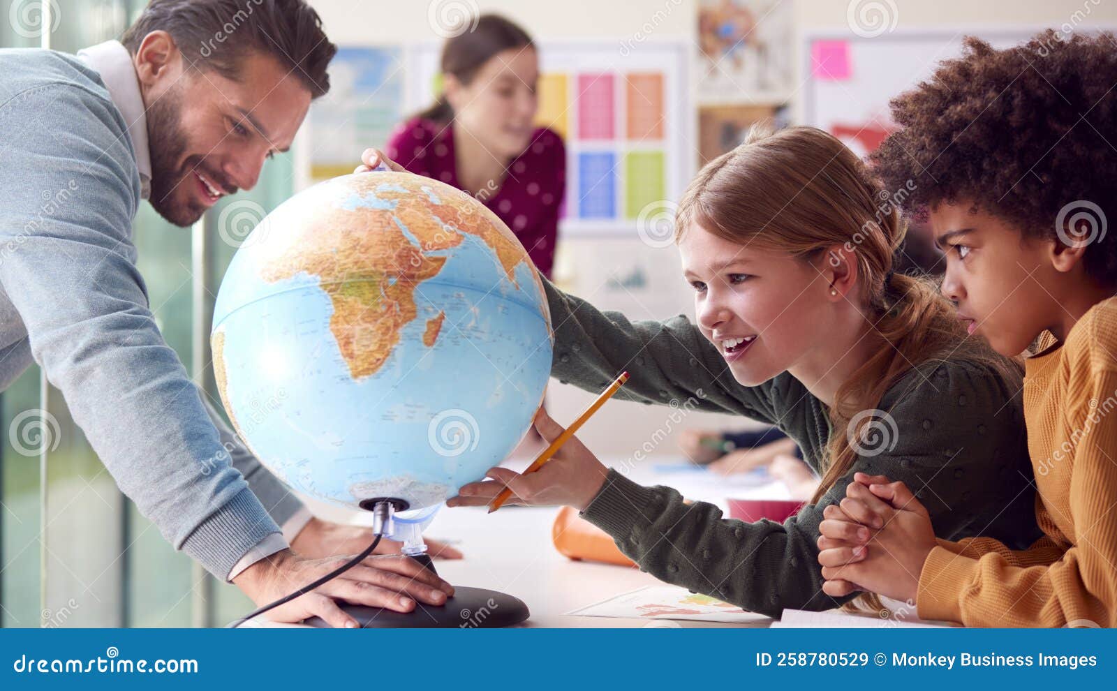 Group of Multi-Cultural Students with Teachers in Classroom Looking at ...
