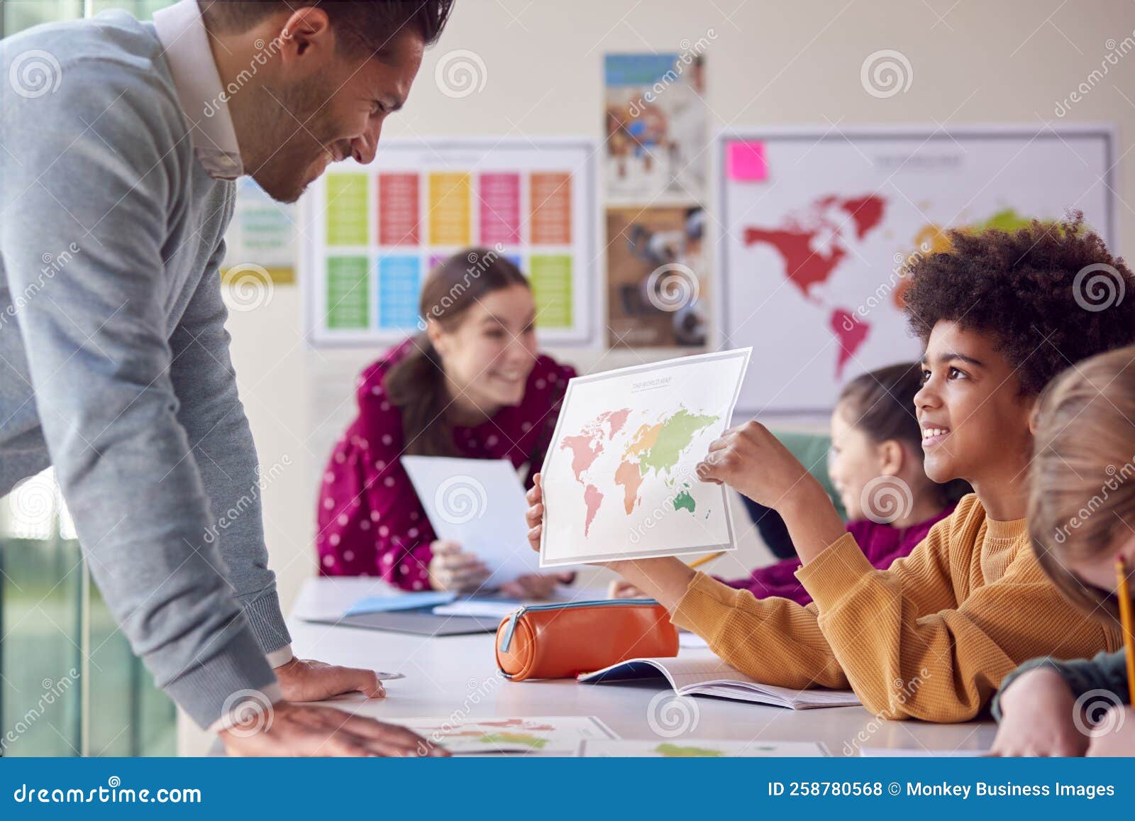 Group of Multi-Cultural Students with Teachers in Classroom Looking at ...