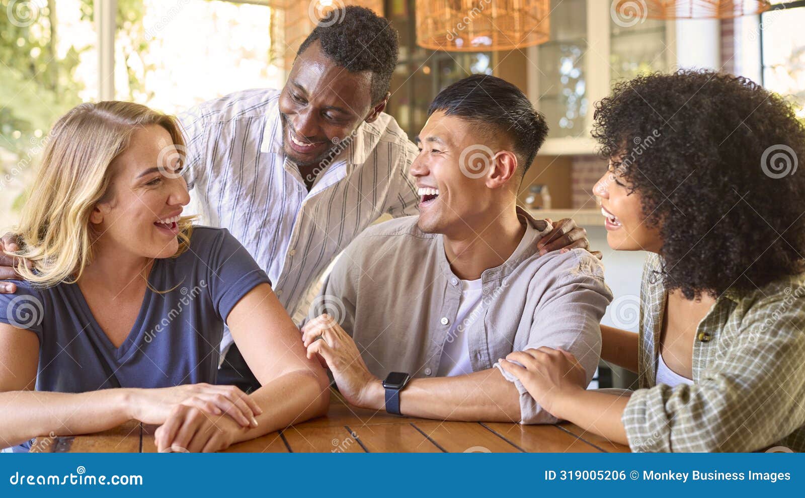 Group Multi-Racial Friends Sitting Around Table at Home Laughing and ...