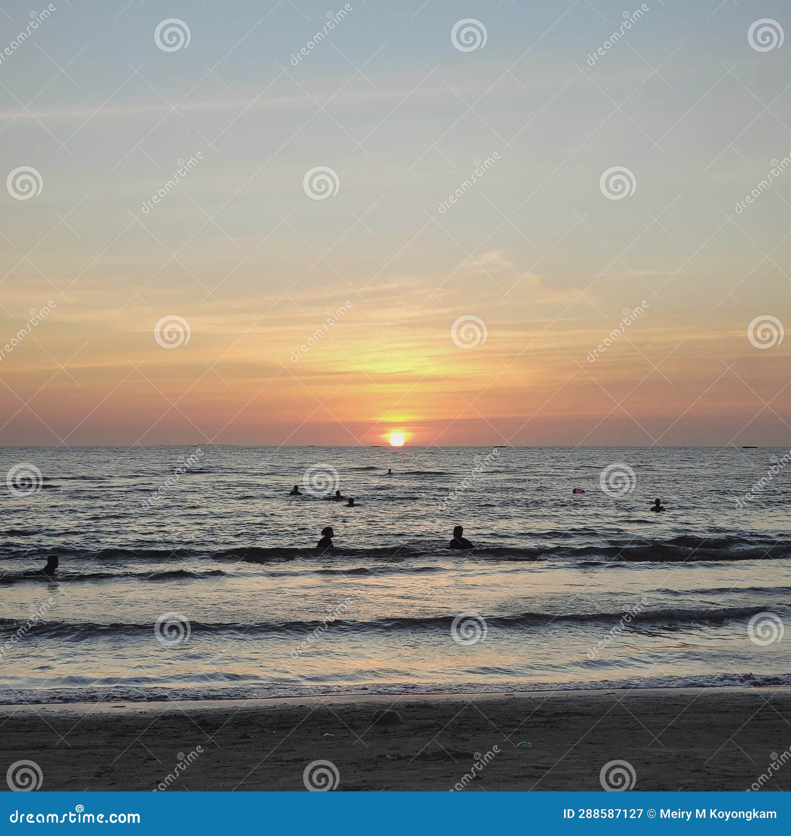 A Group of People Bathing on the Beach while Watching the Sunset ...