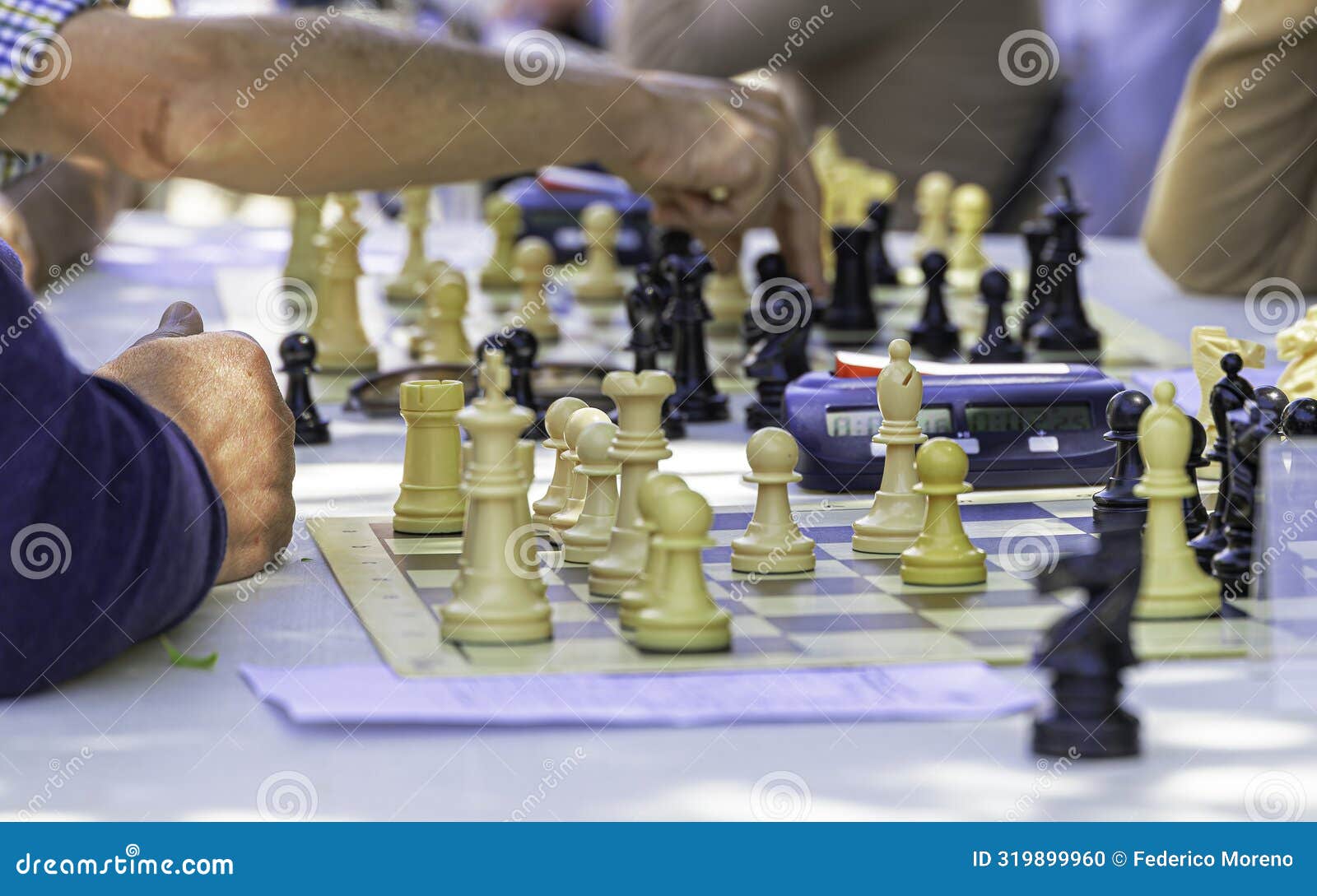 A Group of People Playing Chess with a Timer on the Table Stock Photo ...