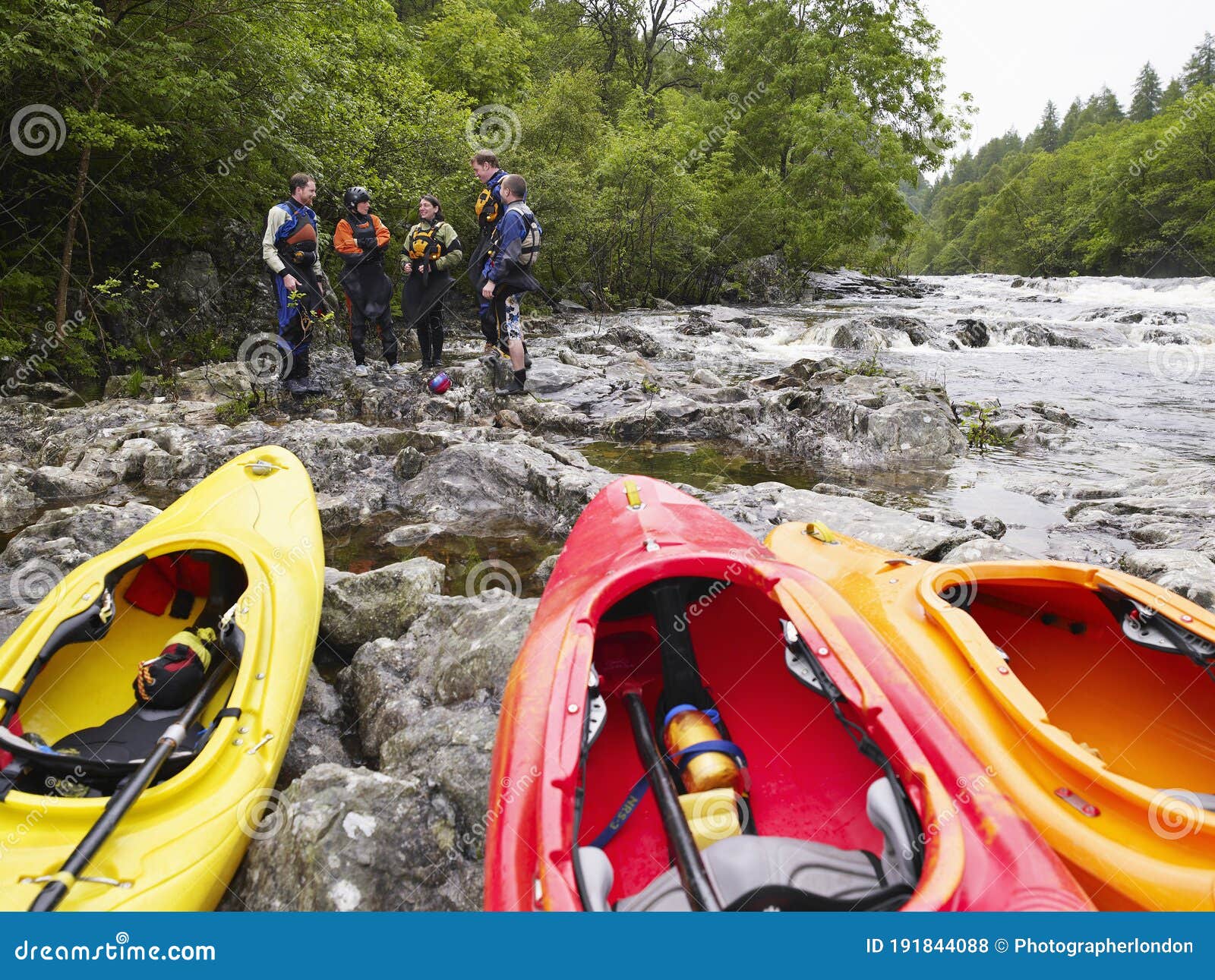 Group of People by River Kayaks in Foreground Stock Photo - Image of ...