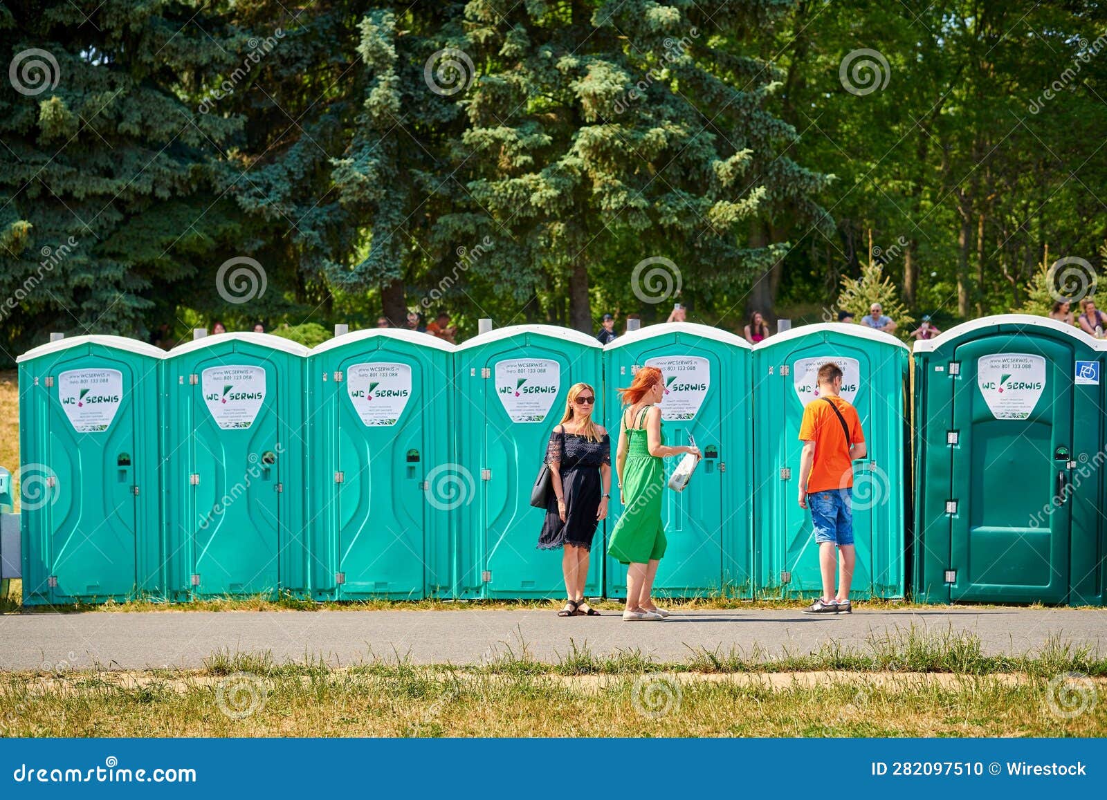 Group of People Standing in Front of a Row of Plastic Toilet Cabins in ...