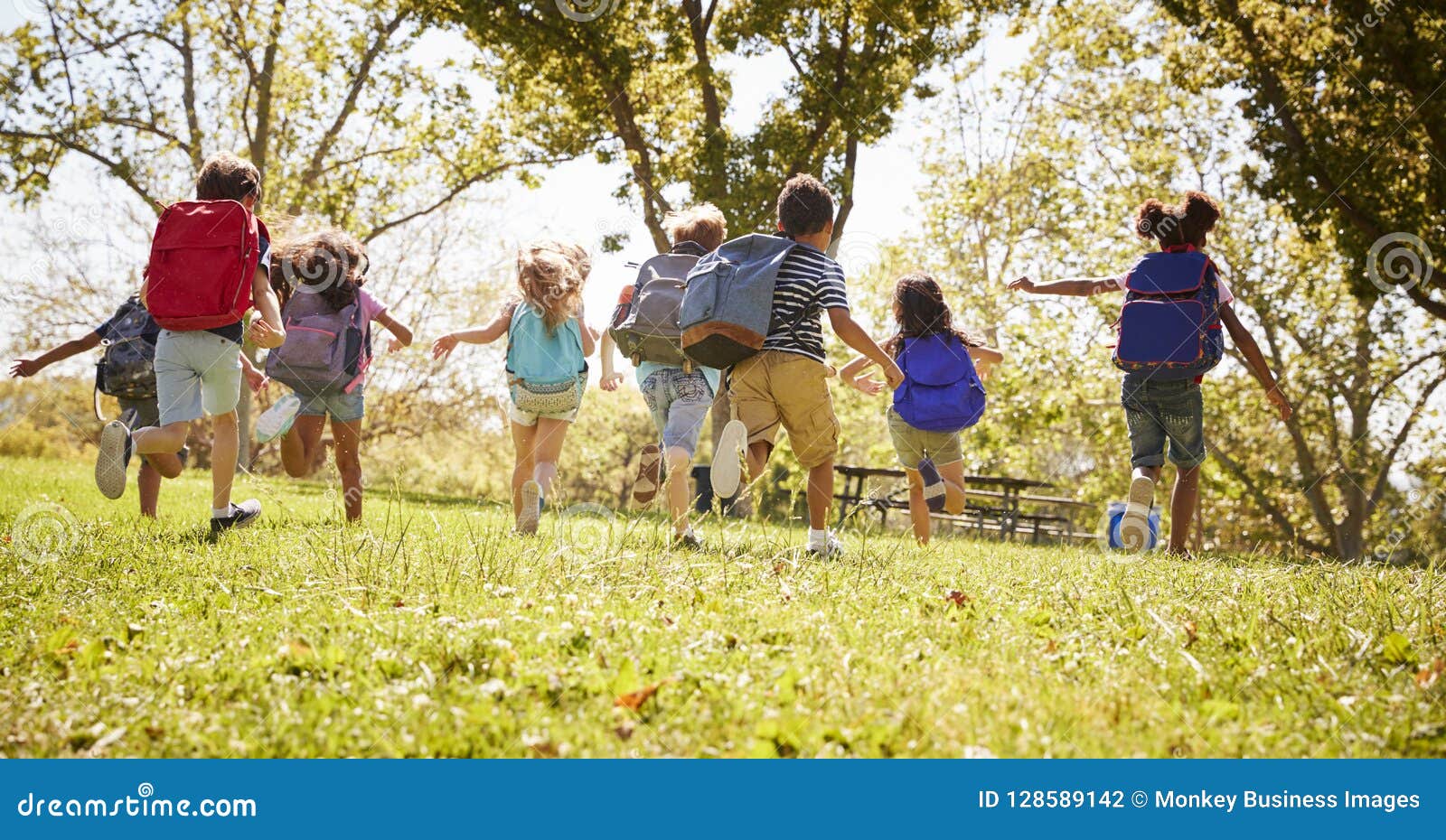 Group of Schoolchildren Running in a Field, Back View Stock Photo ...