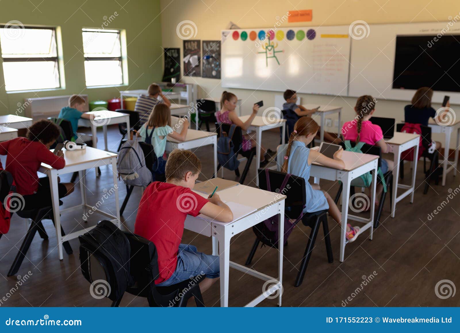 Group of Schoolchildren Sitting at Desks Working in an Elementary ...