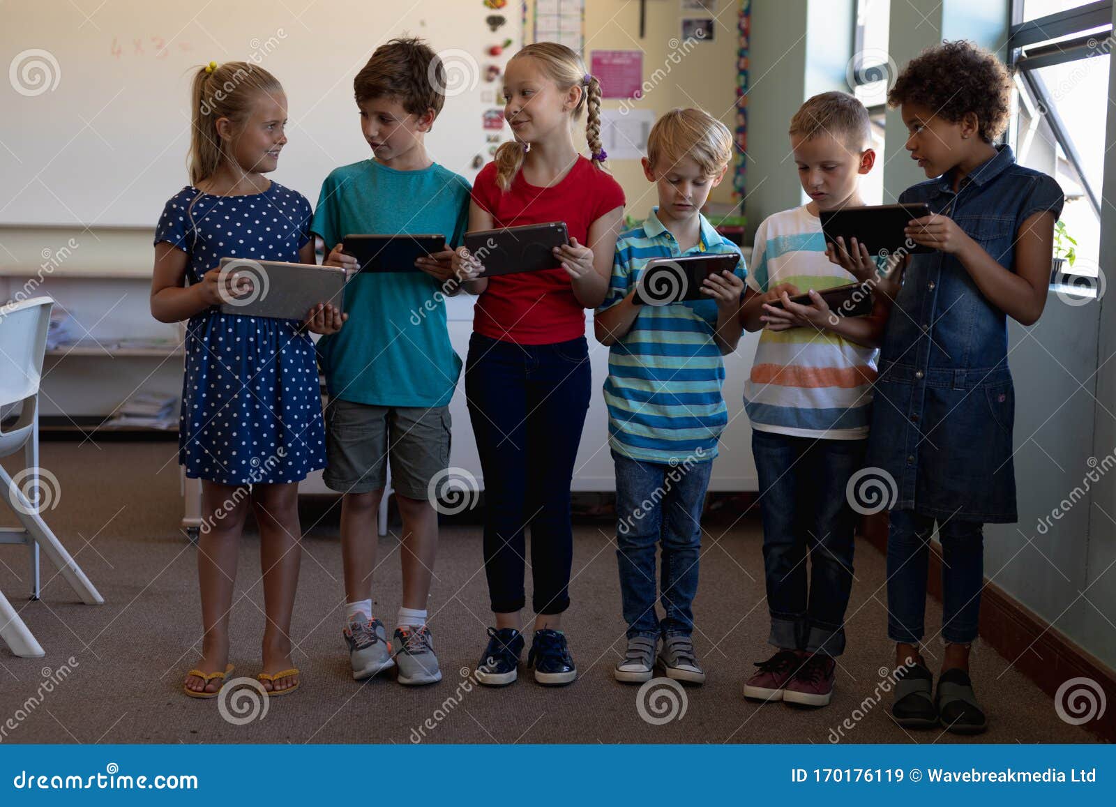 Group of Schoolchildren Standing in a Line and Using Tablet Computers ...
