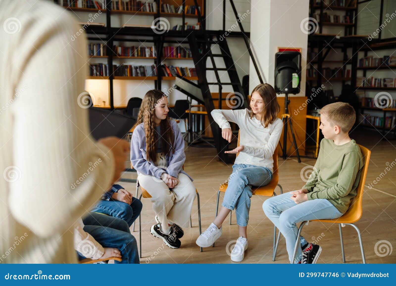 Group of Schoolkids Discussing Something while Sitting in Library Stock ...