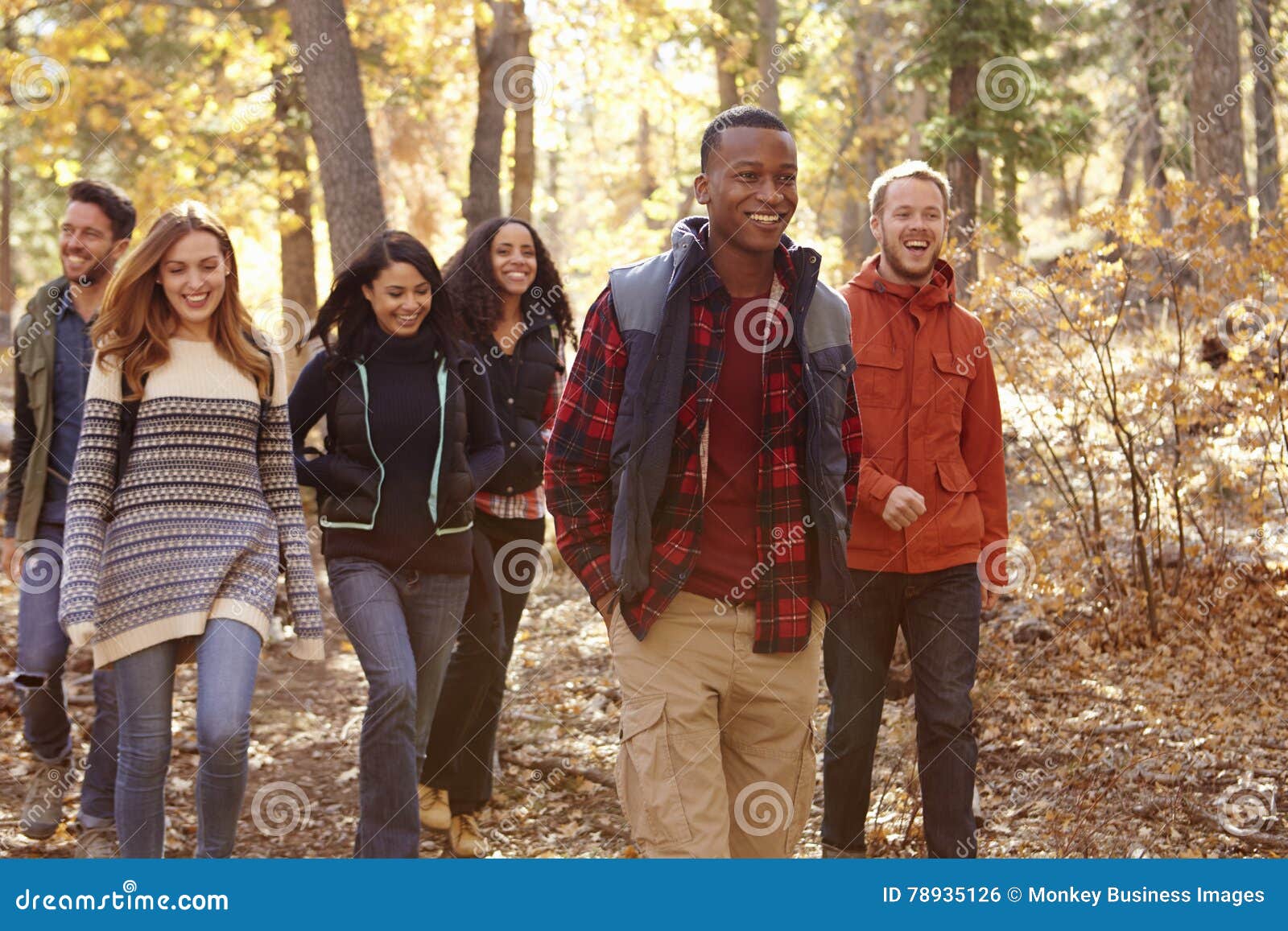 Group Of Four Friends Hiking Together Through A Forest