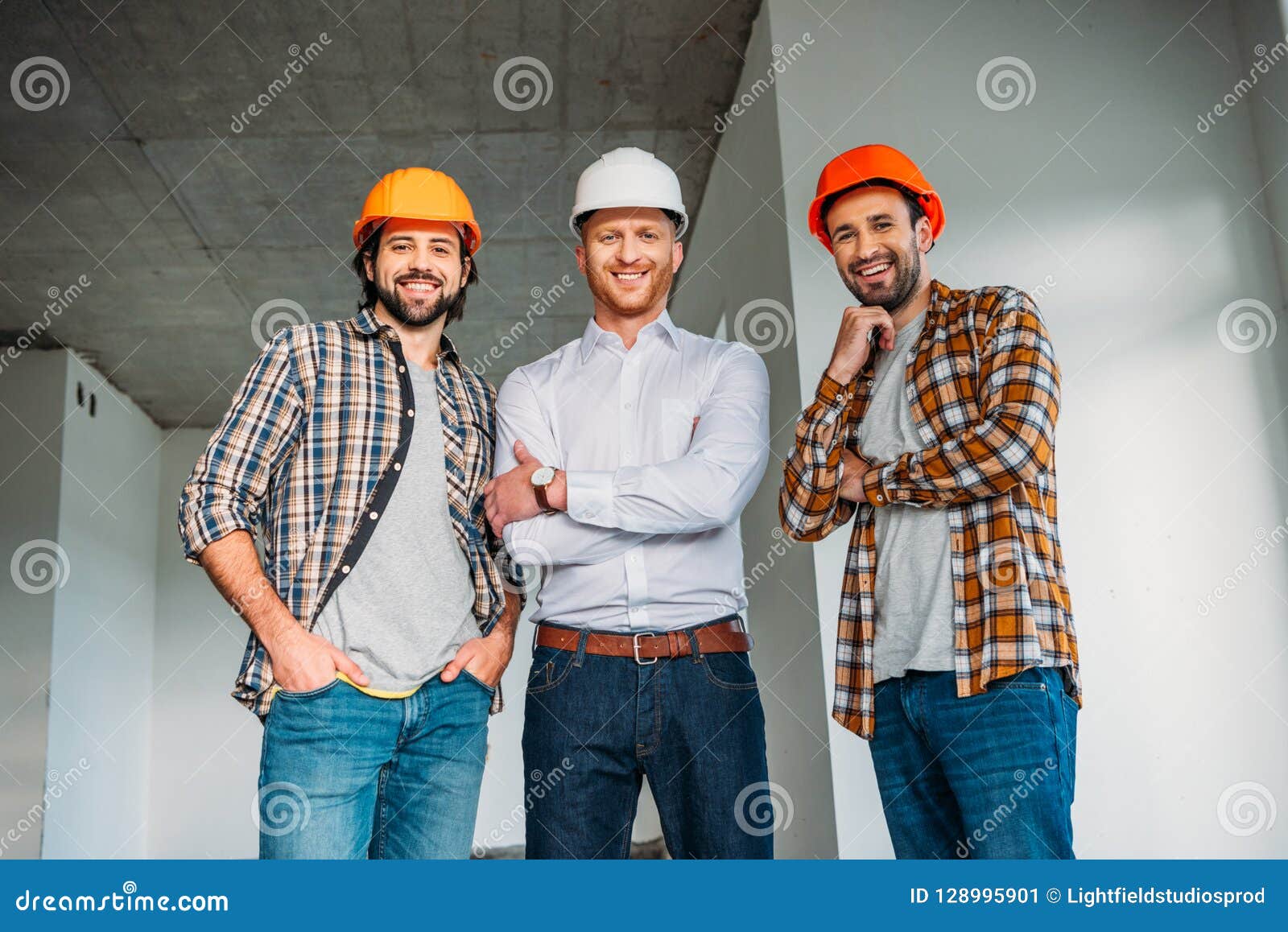 Group of Smiling Architects Inside of Constructing Building Looking ...