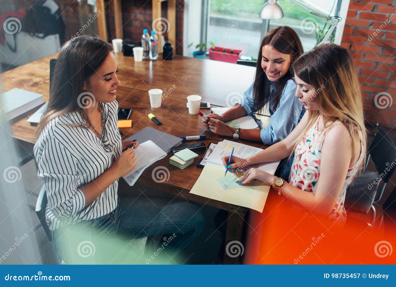 Group of Smiling Creative Women Discussing a Project Sitting Around ...