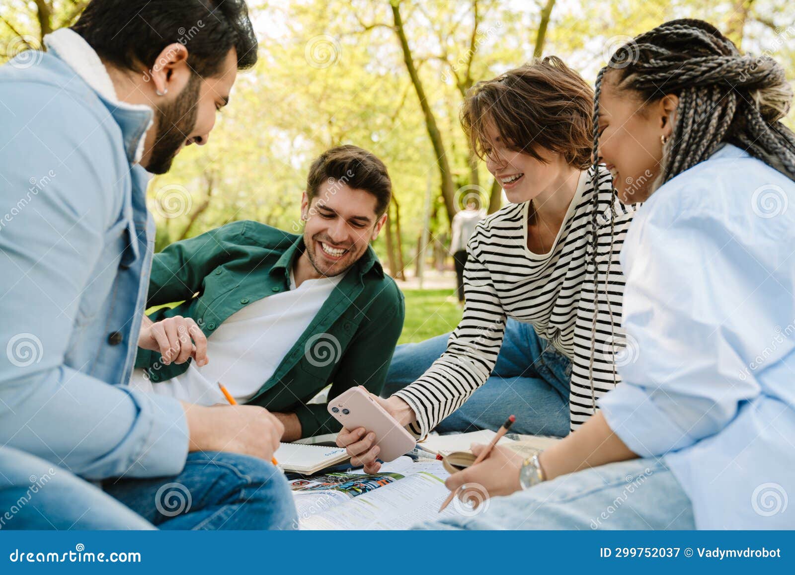 Group of Smiling Students Using Smartphone while Spending Time Together ...