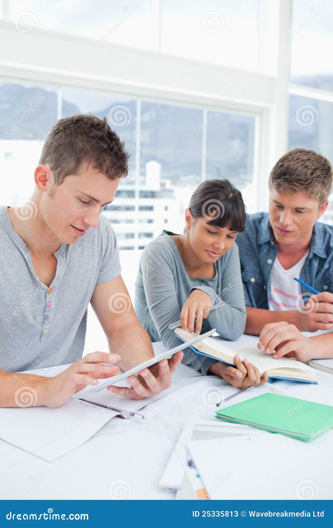 A Group of Students Sit Together Using a Tablet and a Book To St Stock ...