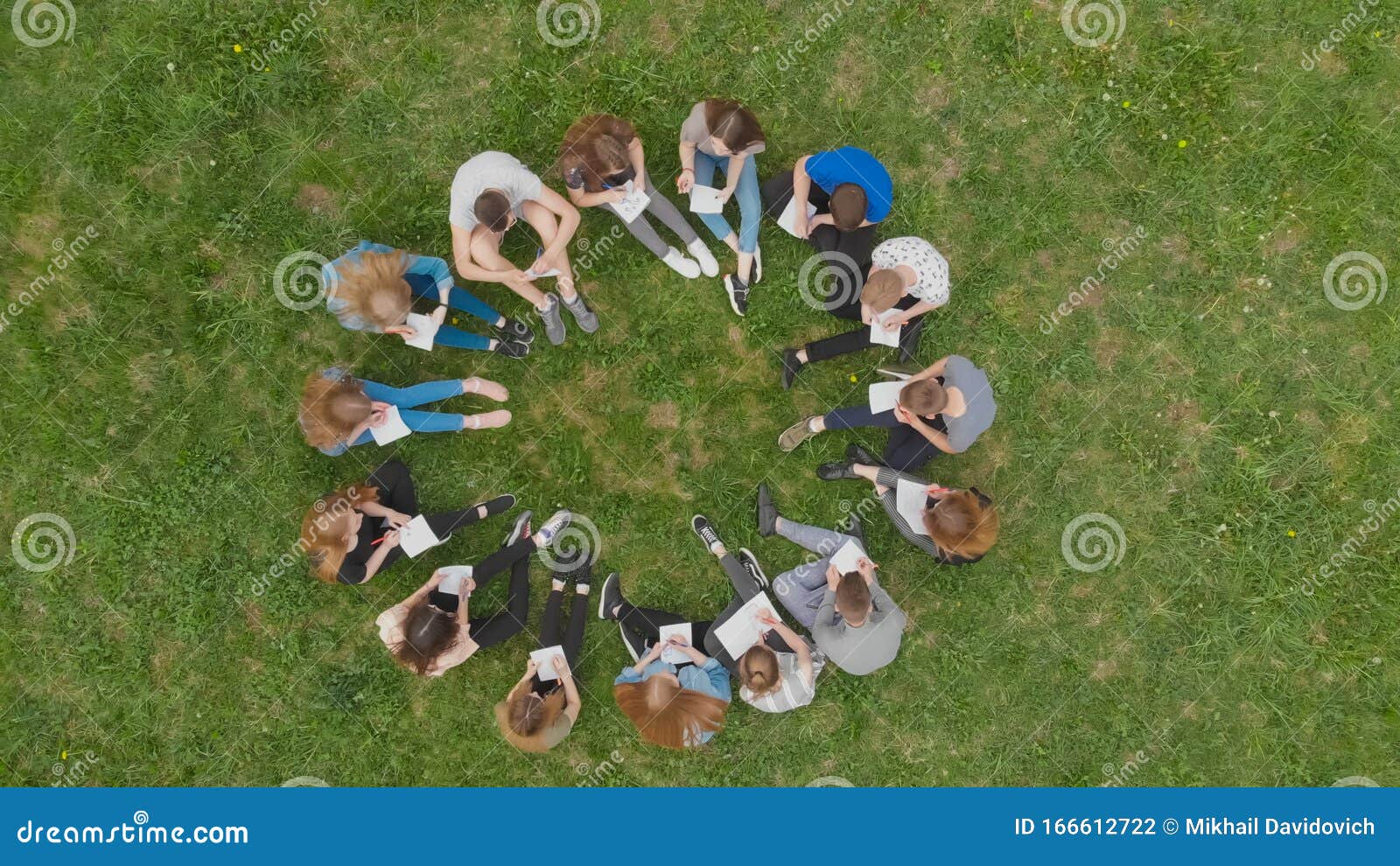 A Group of Students are Sitting in a Circle and Books on the Grass ...