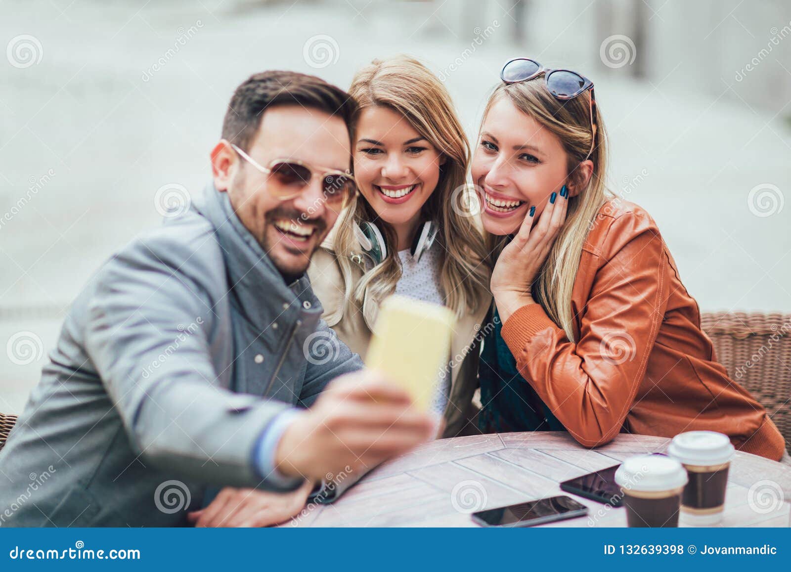 Group of Three Friends Using Phone in Outdoor Cafe Stock Photo - Image ...