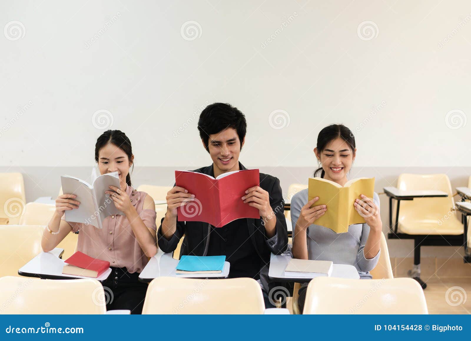 Group of Three Students Reading Book Together in Classroom Stock Photo ...