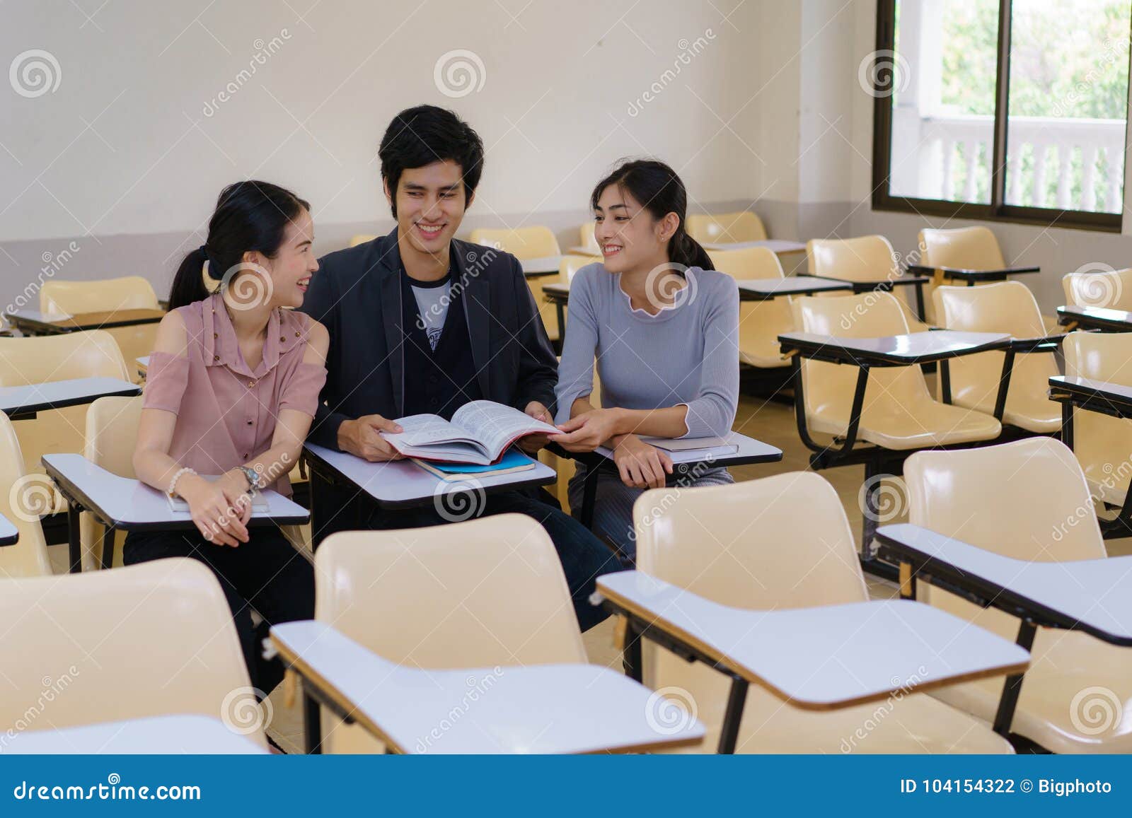 Group of Three Students Reading Book Together in Classroom Stock Photo ...