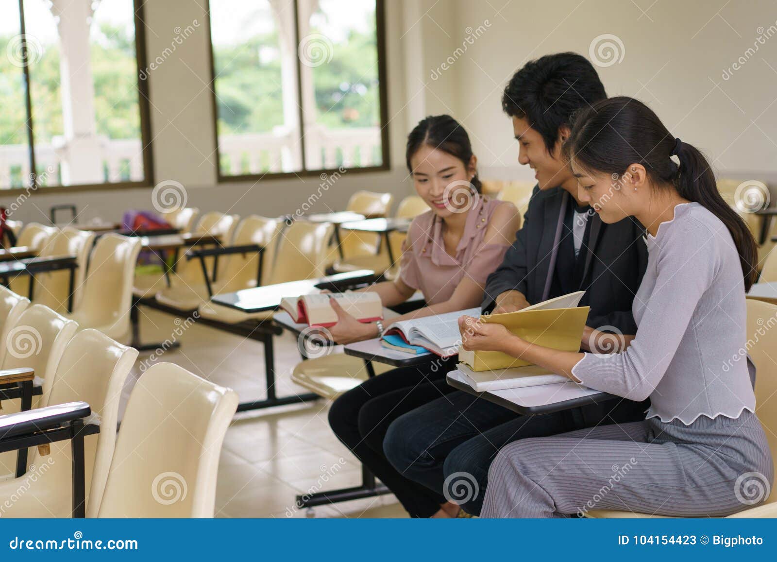Group of Three Students Reading Book Together in Classroom Stock Image ...