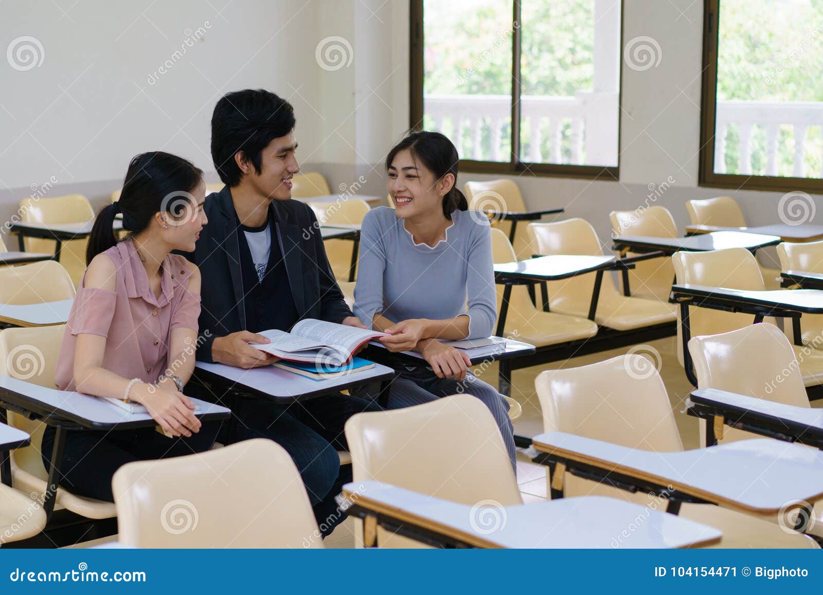 Group of Three Students Reading Book Together in Classroom Stock Image ...