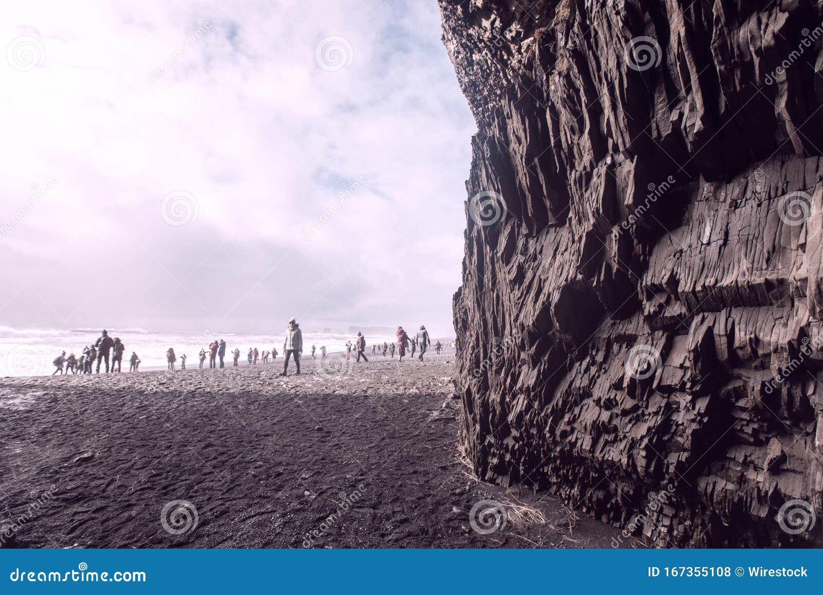 Group of Travelers on the Sandy Beach with the Stiff Rock Formations on ...