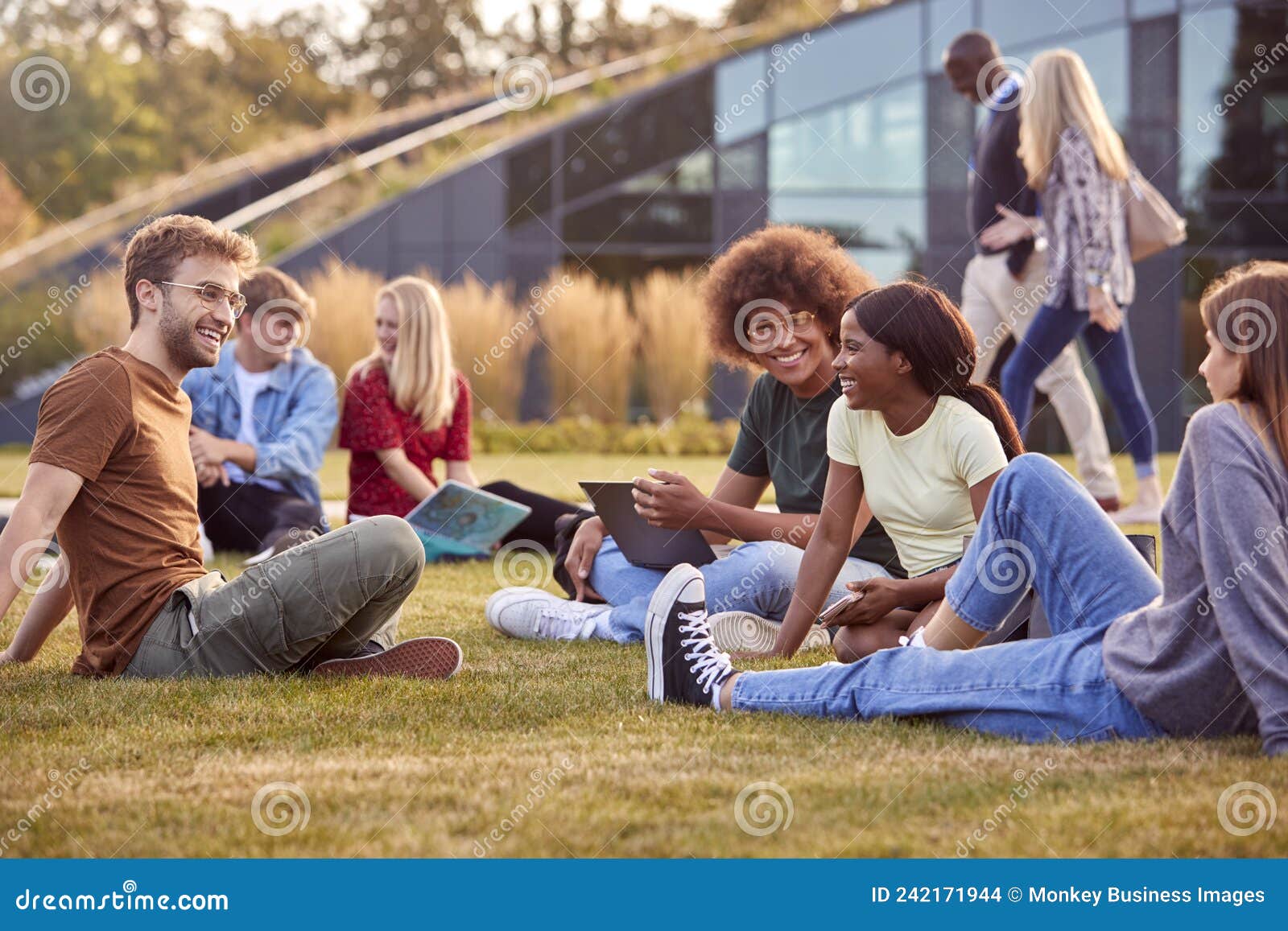 Group of University or College Students Sit on Grass Outdoors on Campus ...