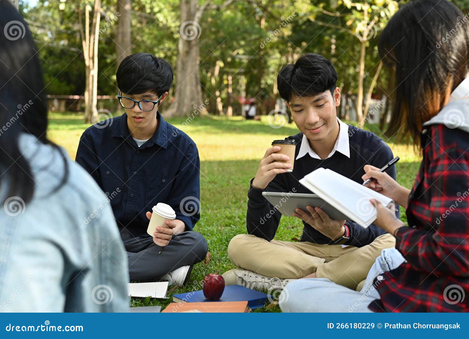 Group of University Students Talking with and Reading Book while ...