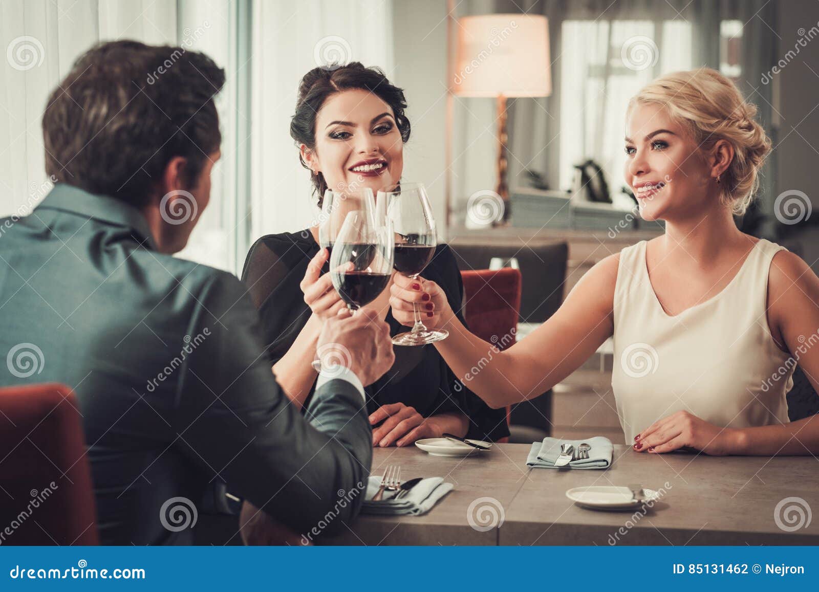 Group Of Wealthy People Clinking Glasses Of Red Wine In Restaurant
