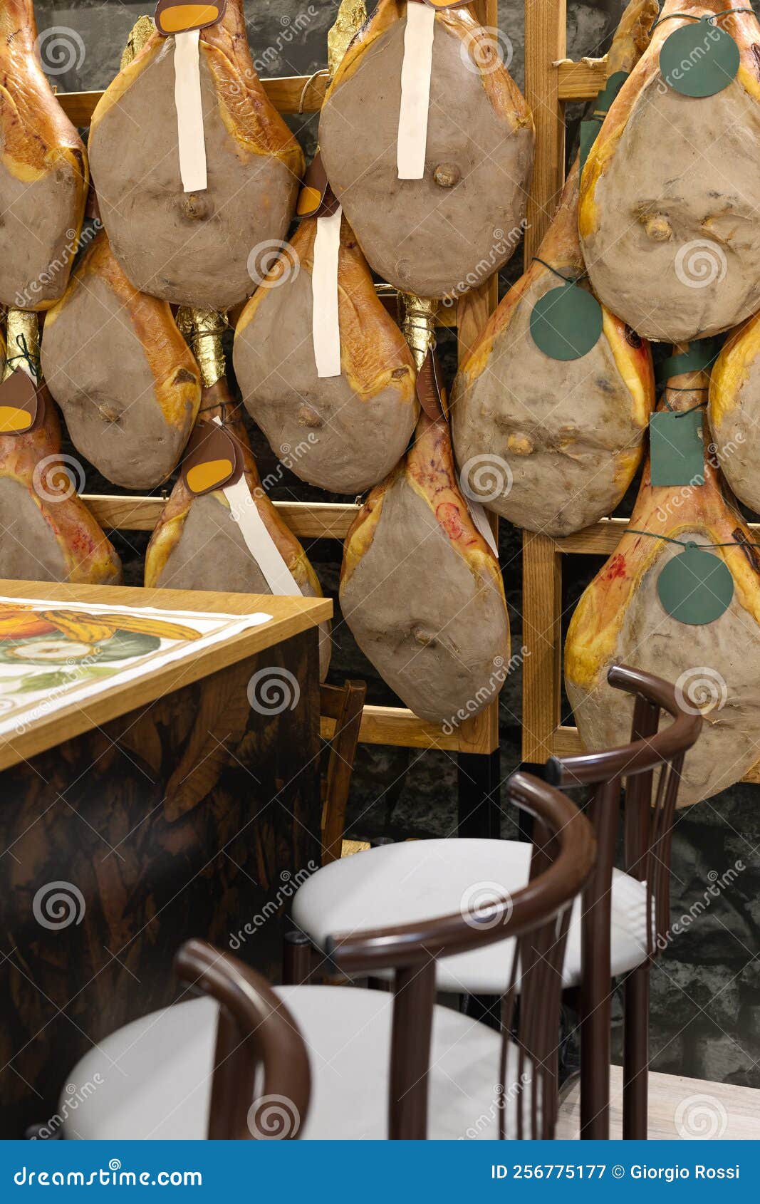 Group of Whole Raw Hams Hung on a Wall and a Table and Chairs for ...