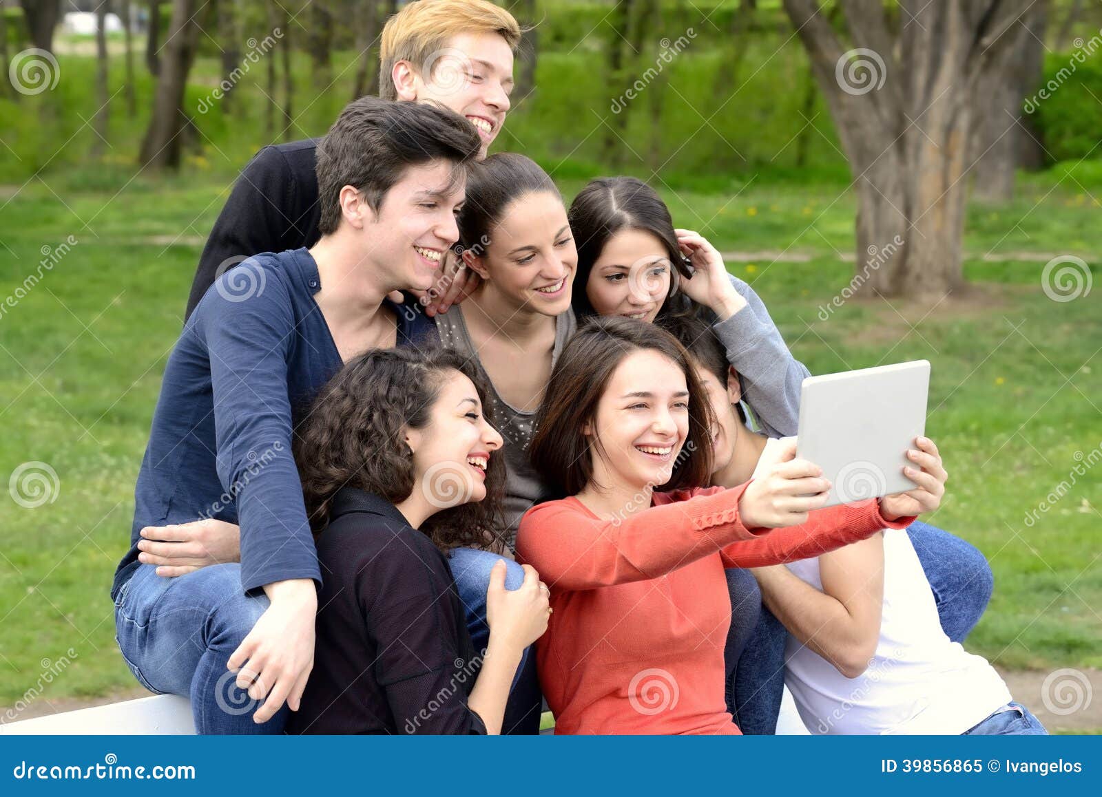 Group of Young Adults Browsing a Tablet Outside Stock Image - Image of ...