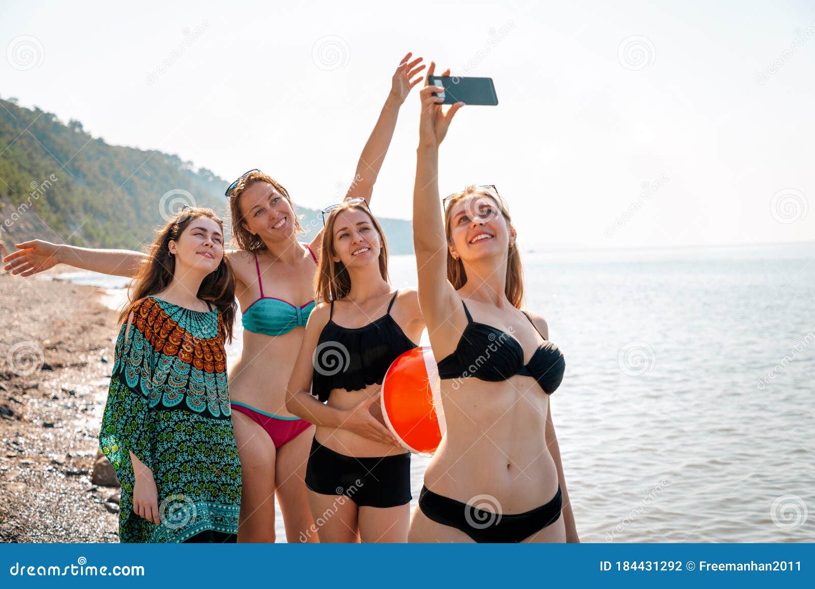 A Group Of Young Caucasian Women Take Selfies On The Beach In The