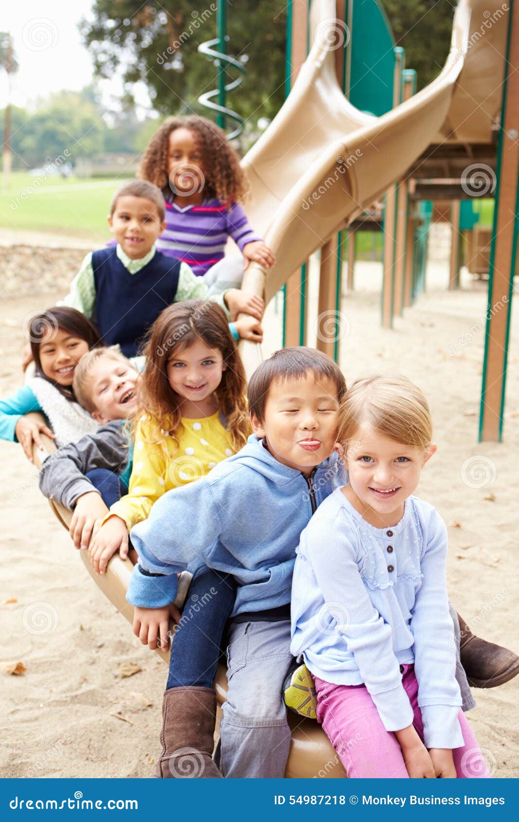 Group of Young Children Sitting on Slide in Playground Stock Photo ...