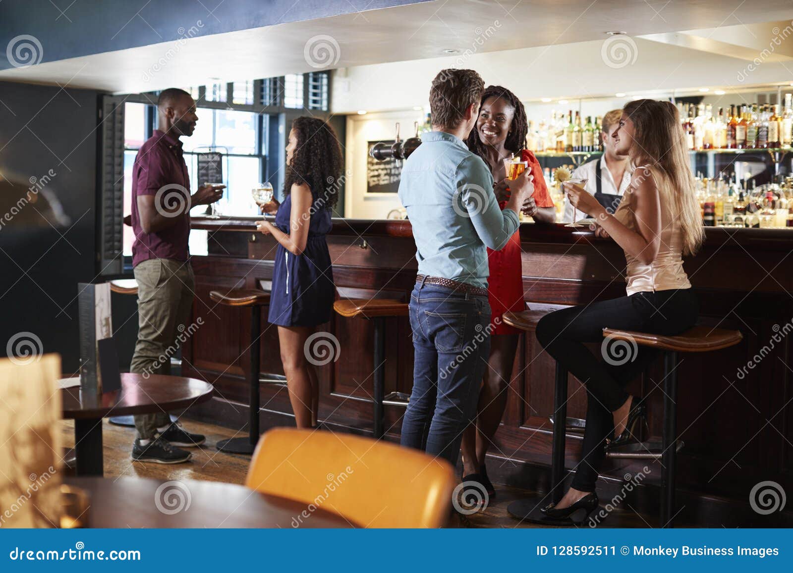 Group of Young Friends Relaxing in Bar Standing at Counter Stock Image ...