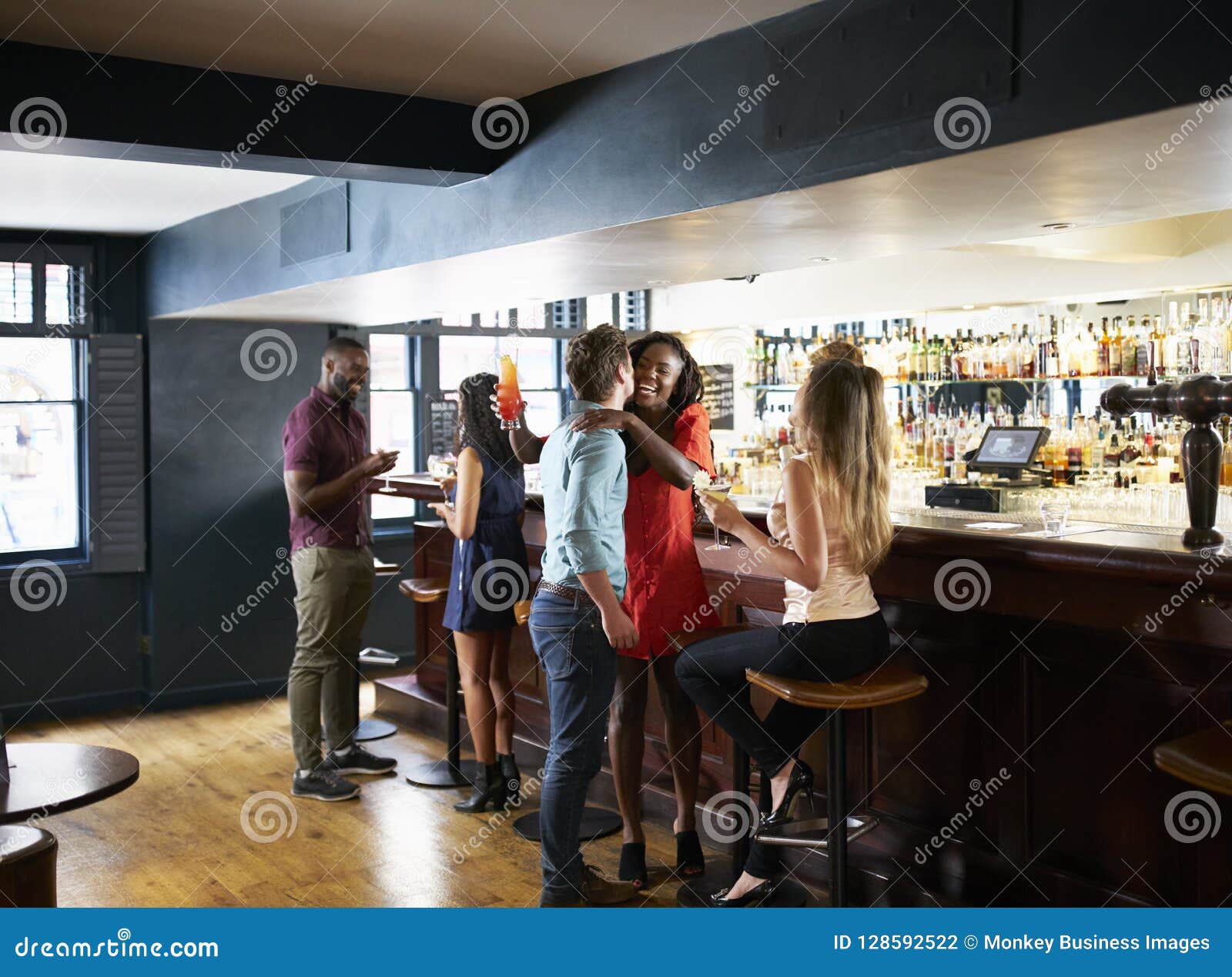 Group of Young Friends Relaxing in Bar Standing at Counter Stock Photo ...