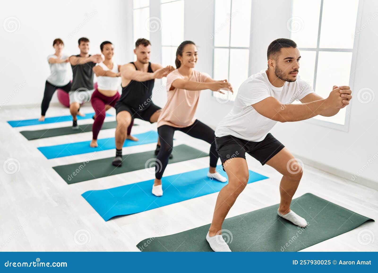 Group of Young Hispanic People Concentrate Training Legs Exercise at ...