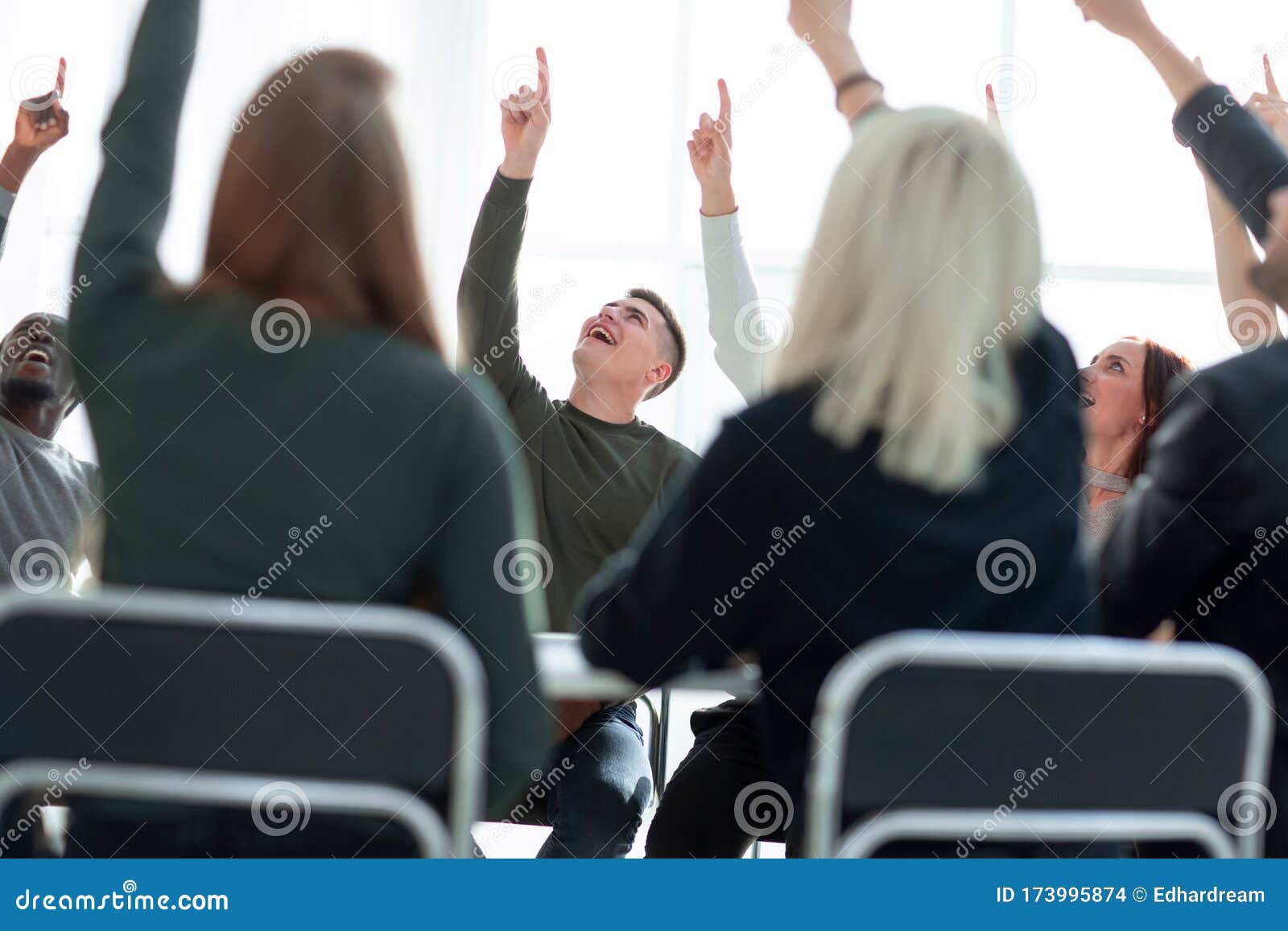 Group of Young People Sitting at a Large Table and Pointing Up Stock ...