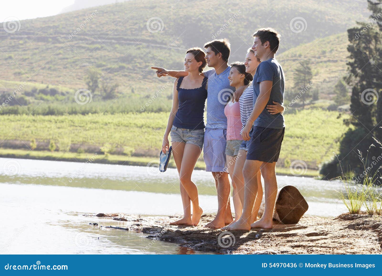 Group of Young People Standing at Shore of Lake Splashing Water Stock ...