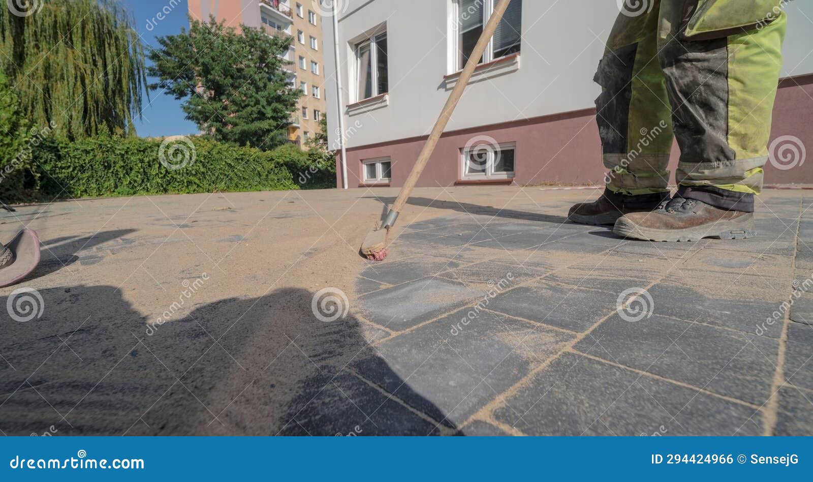 Sweeping Sand into the Joints of a Yard Paved with Paving Stones. Stock ...