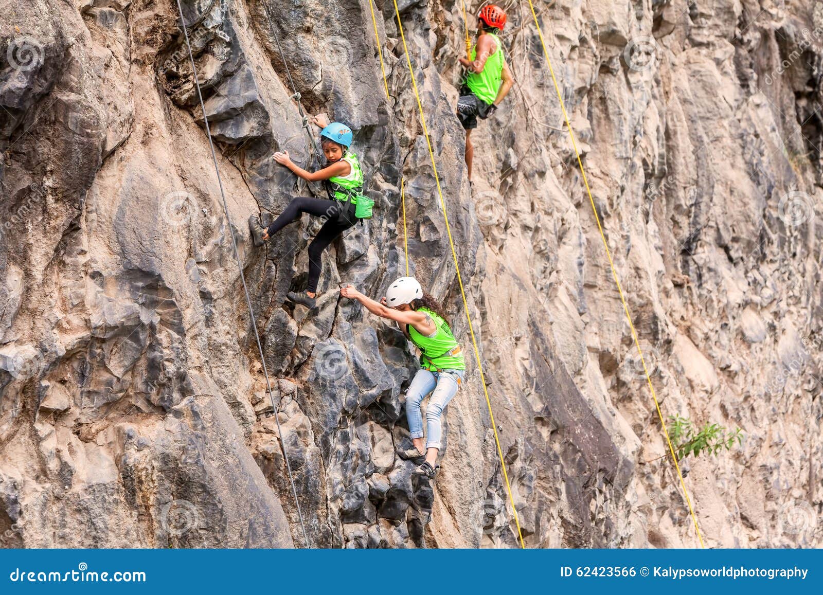 Grupo De Escaladores Del Adolescente Que Suben Una Pared De La Roca
