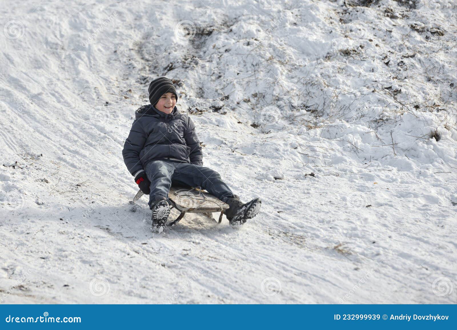 The Guy Goes Down on a Sled on a Snowy Hill in Winter Stock Image ...
