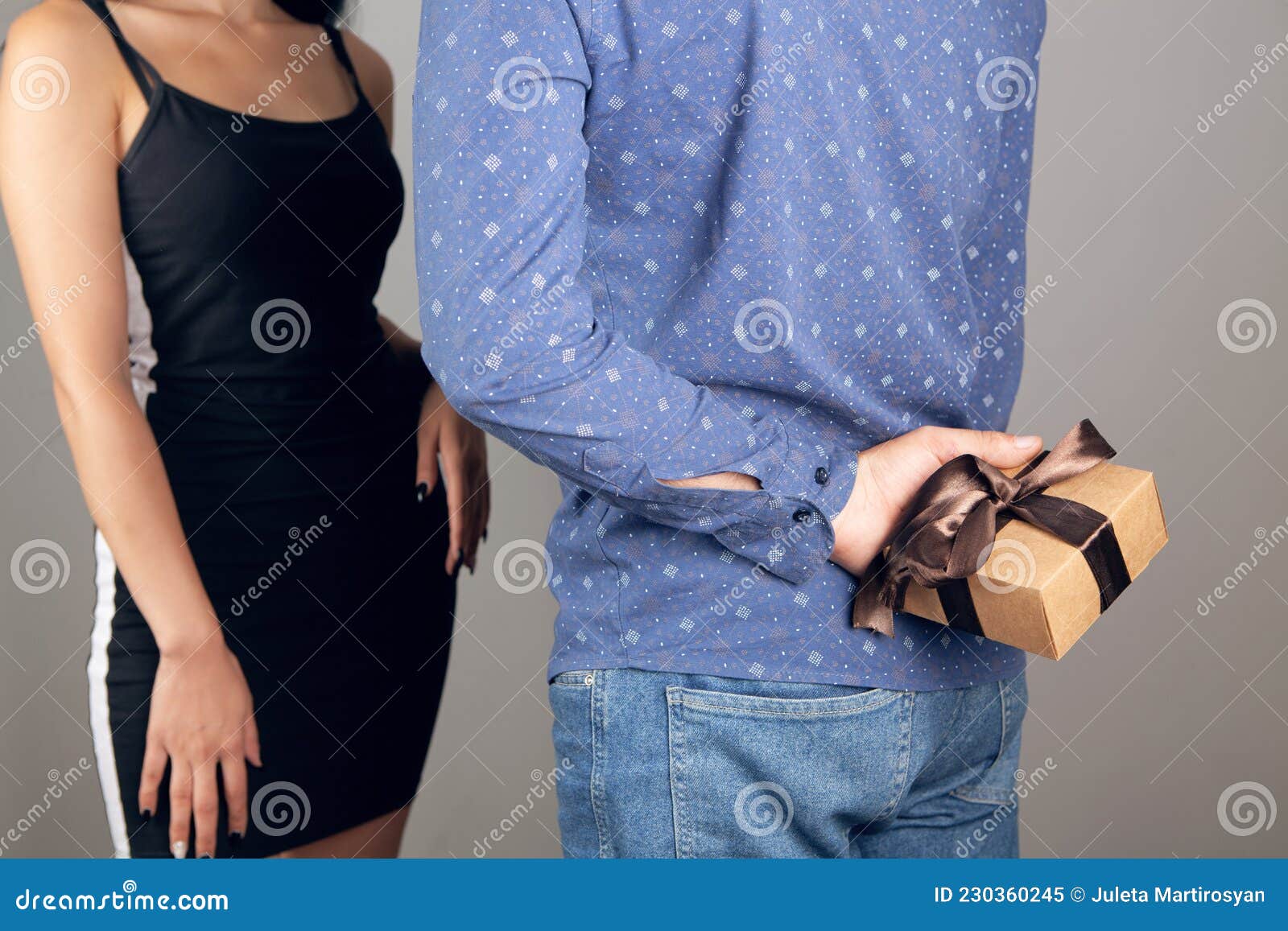 A Guy Holding a Gift from Behind while Standing in Front of a Girl ...
