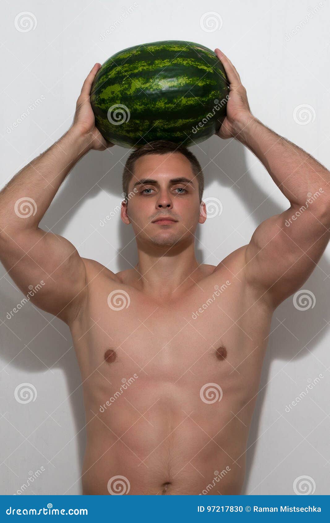 The Guy is Holding a Huge Watermelon on His Head. a Guy with a Bare ...