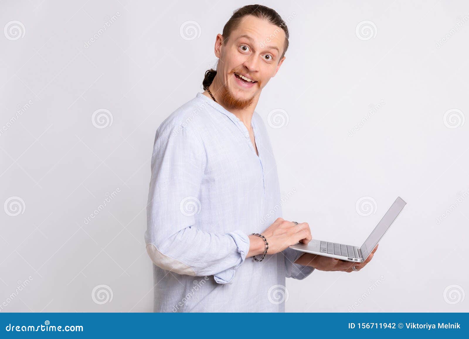 A Guy in a Light Blue Shirt Holding a Laptop in His Hands, Looking at ...