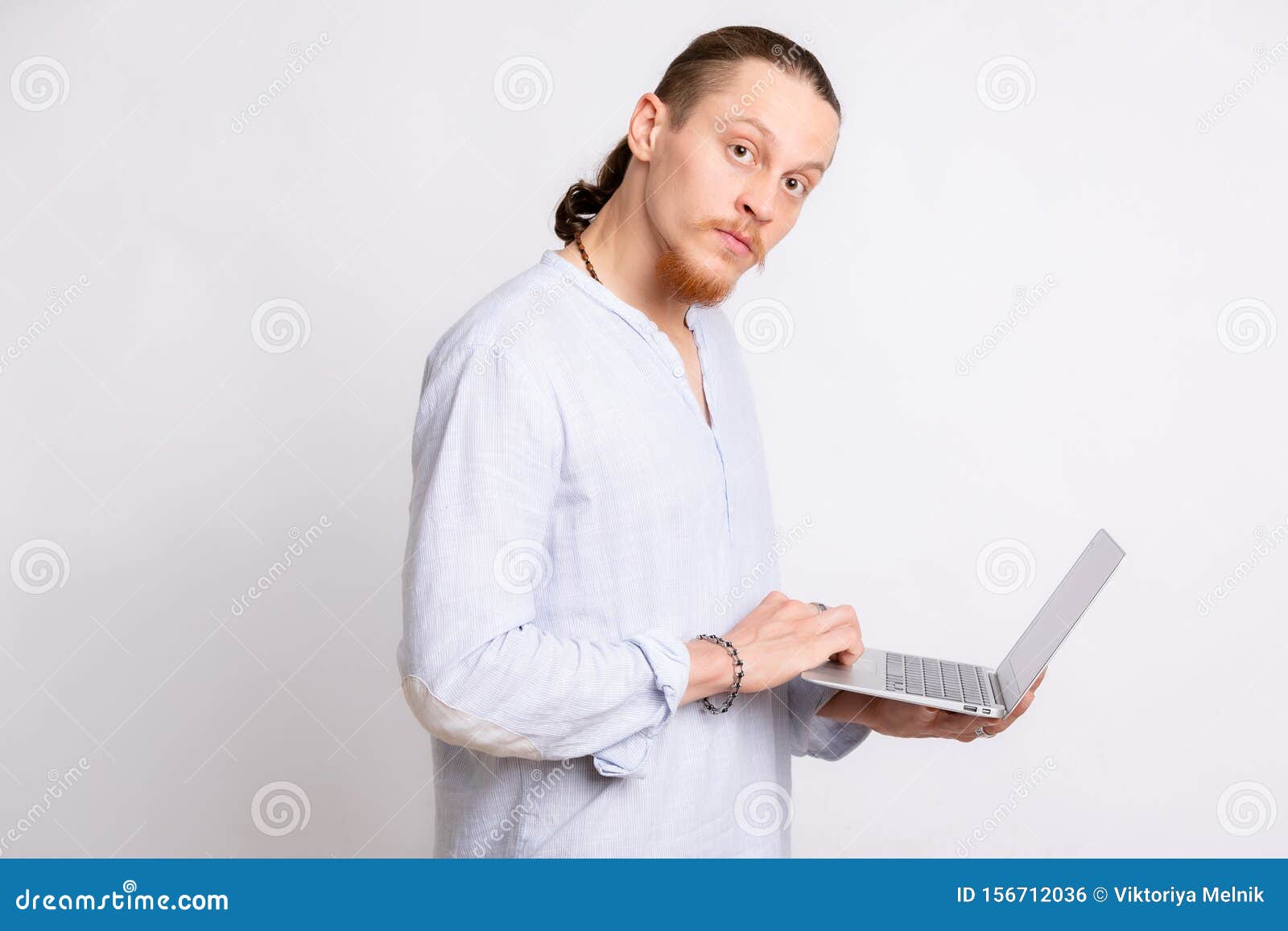 A Guy in a Light Blue Shirt Holding a Laptop in His Hands, Looking at ...