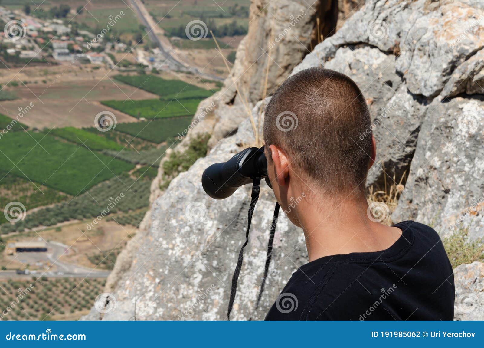 The Guy Looks through Binoculars into the Mountain Peaks Down Stock ...