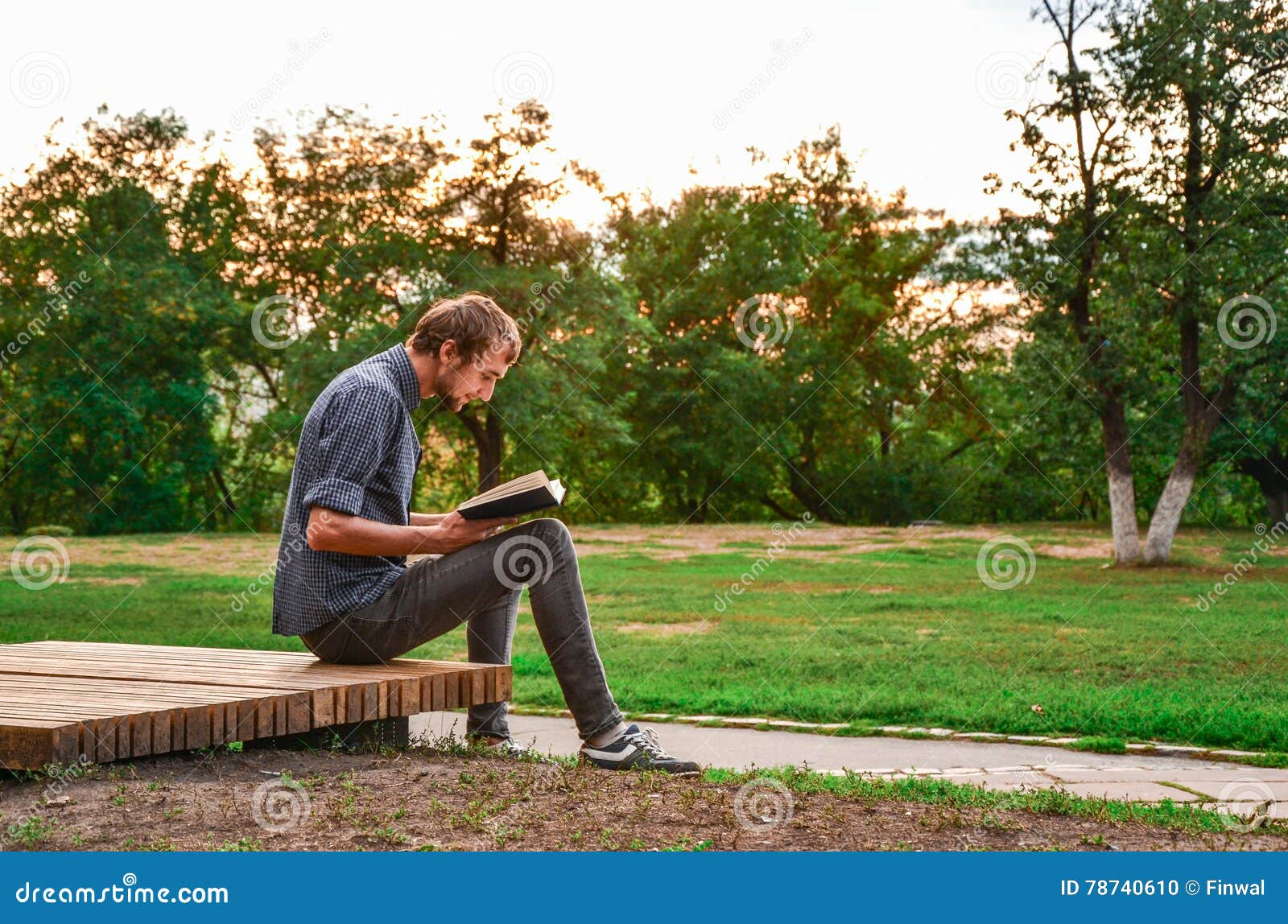 Guy reading book in park stock photo. Image of lantern - 78740610