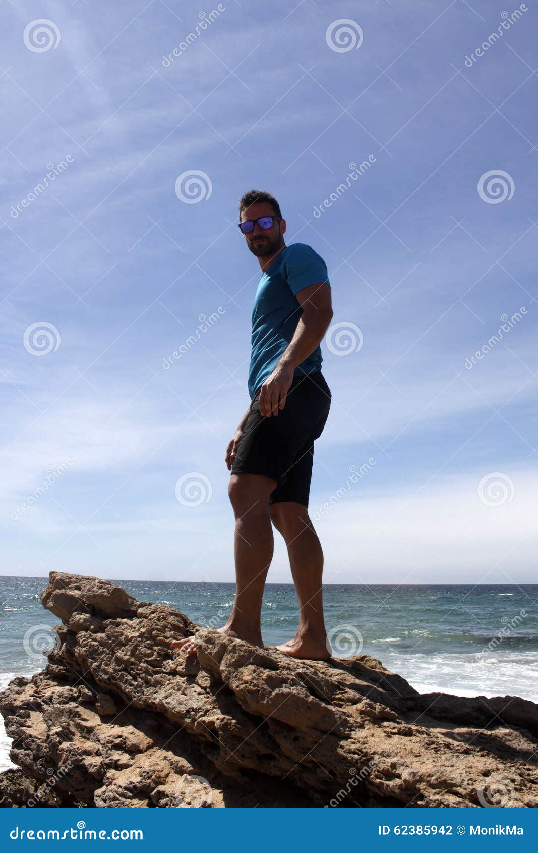 Guy on a rock on the beach stock photo. Image of waves - 62385942