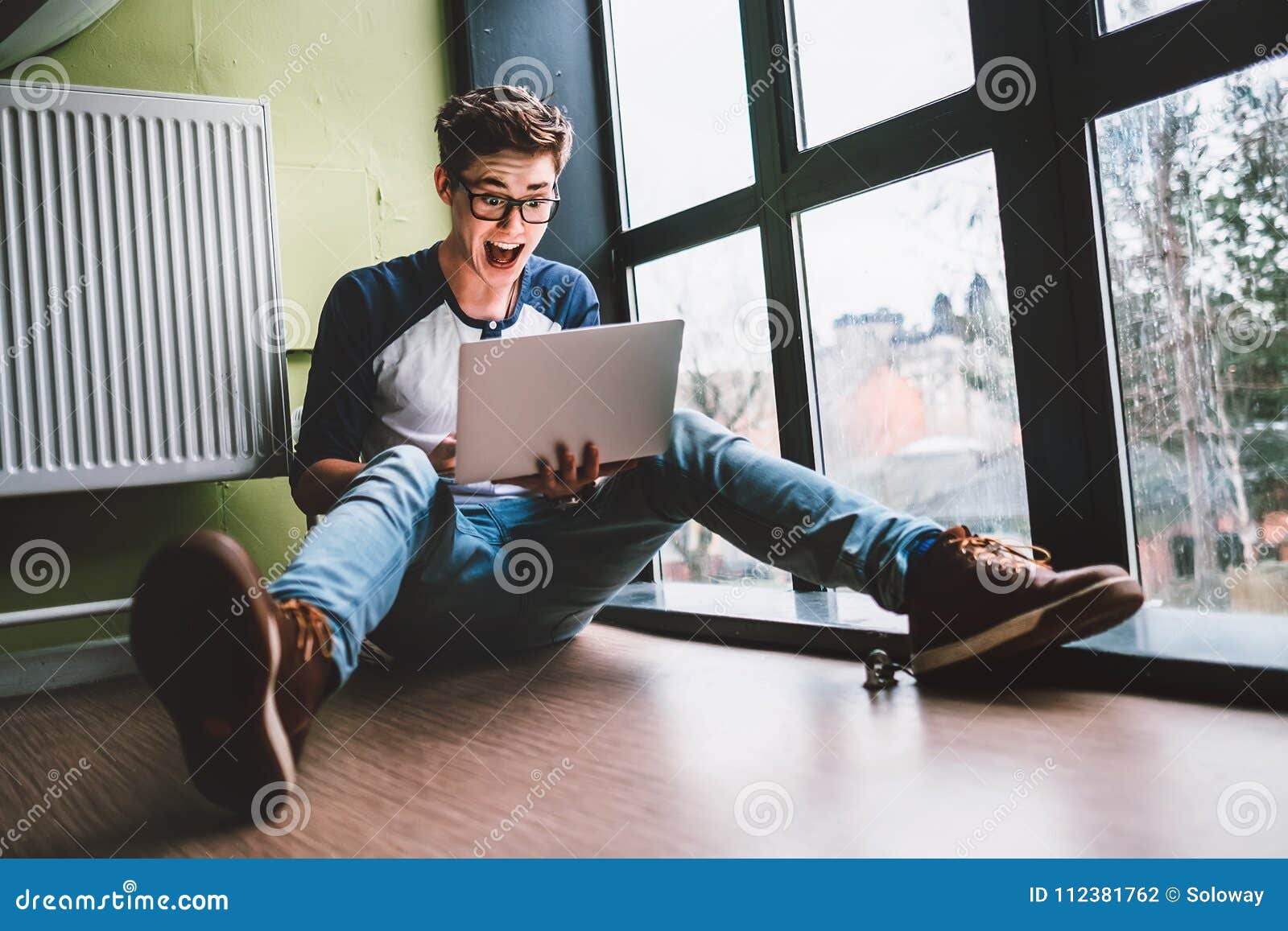 Guy Sits on the Floor and Watches Something Impressing in Laptop Stock ... Guy Sits on the Floor and Watches Something Impressing in Laptop Stock ...