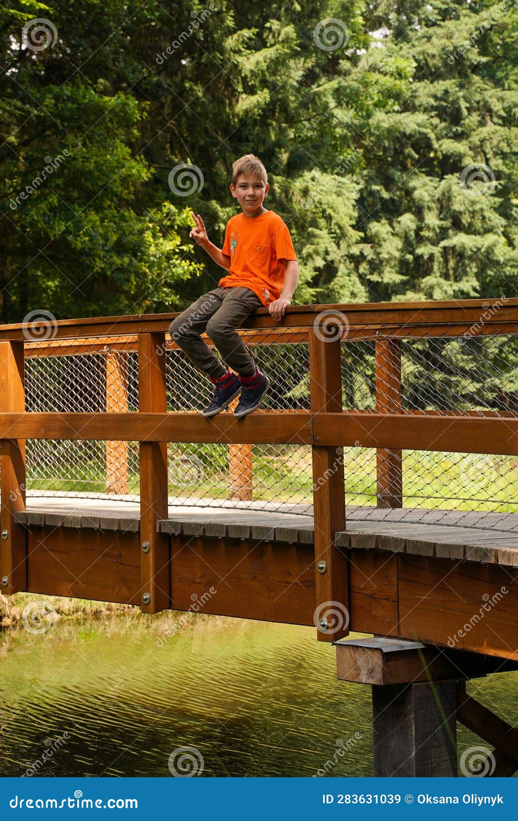 A Guy Sits on the Railing of a Wooden Bridge. Unity with Nature. Stock ...