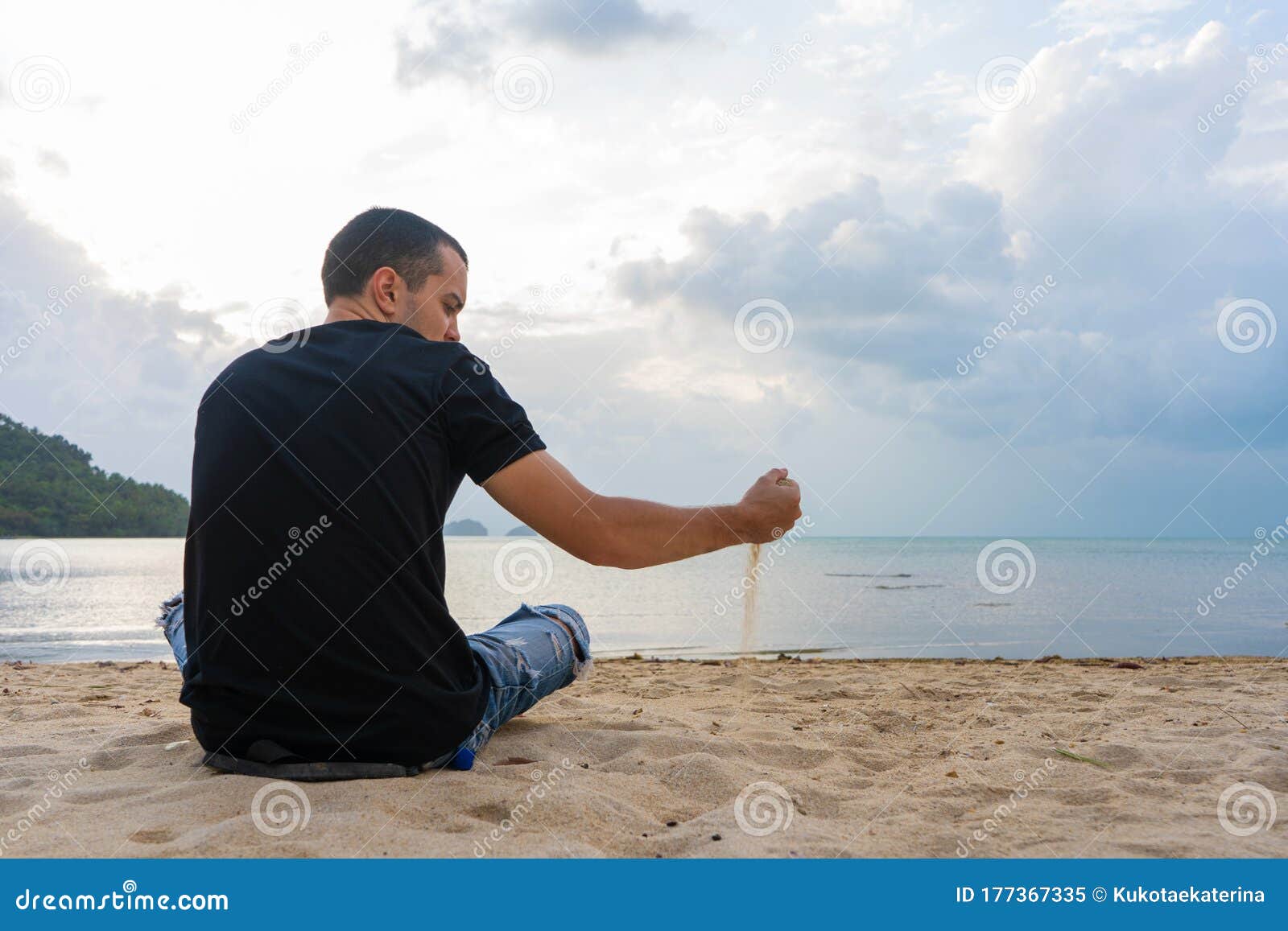 A Guy Sits on a Sandy Beach and Plays with Sand. Pours Sand from His ...