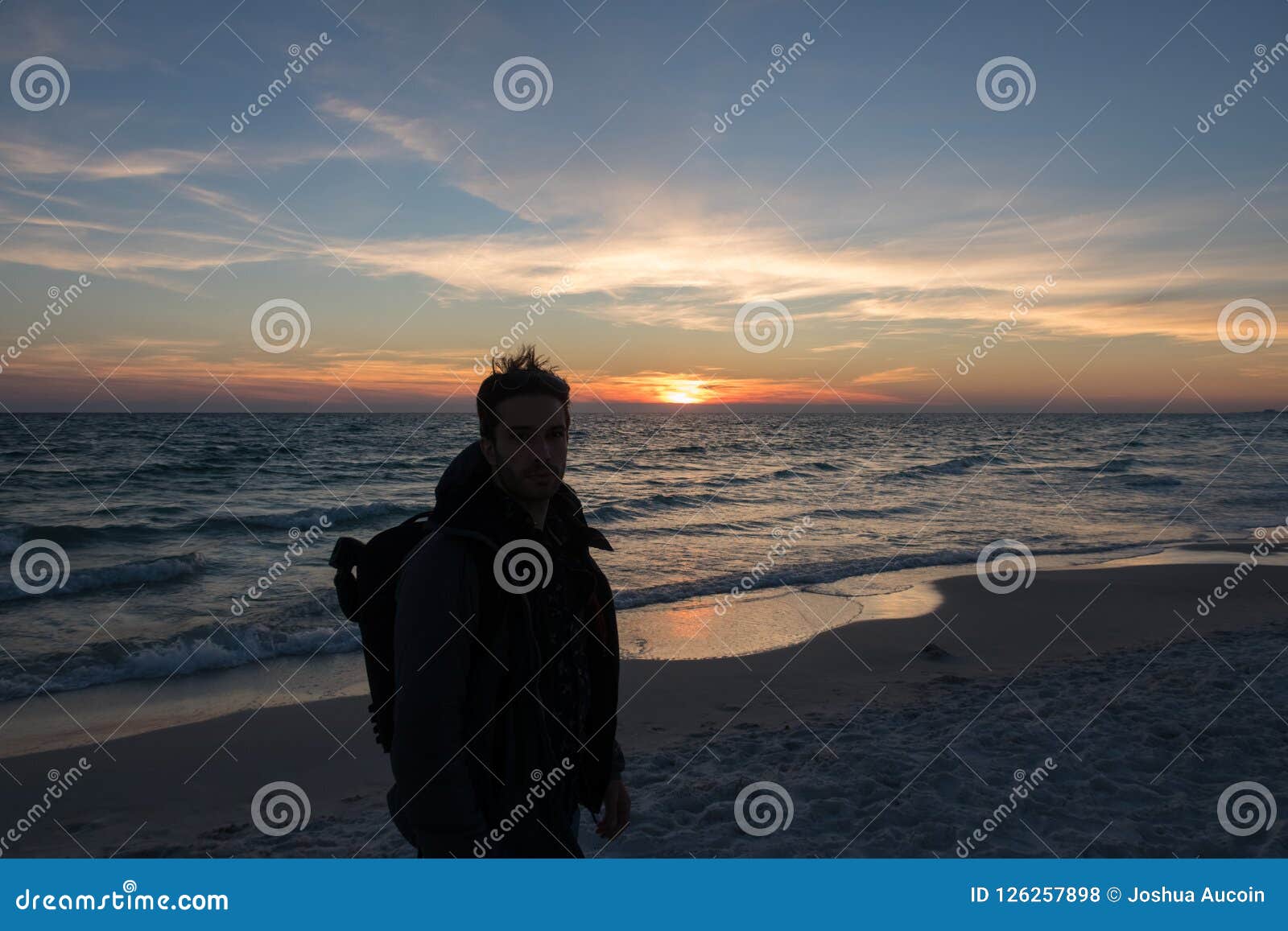 Guy Stands in Front of Dramatic Sunset Over the Ocean Stock Photo ...