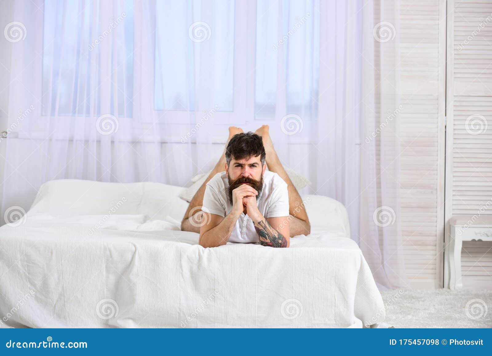 Guy on Strict Face Laying on Edge of Bed on White Sheets. Man Laying on ...